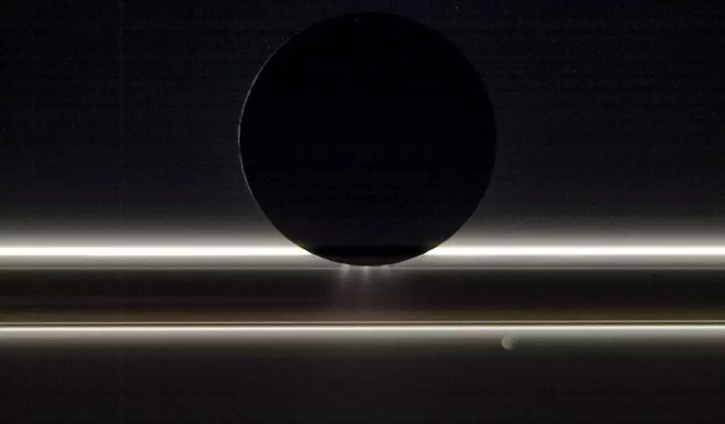 A lua de Saturno Enceladus iluminada pelo sol com jatos fluindo do extremo sul em uma imagem de sonda espacial