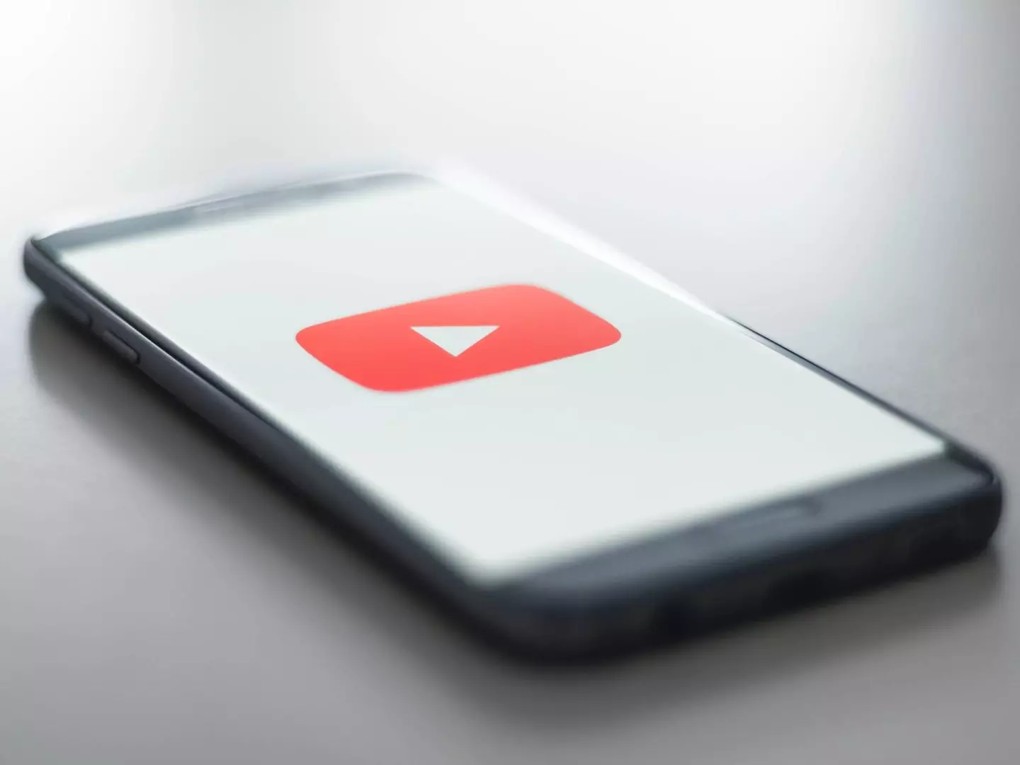 Išmanusis telefonas ant stalo su youtube logotipu ekrane